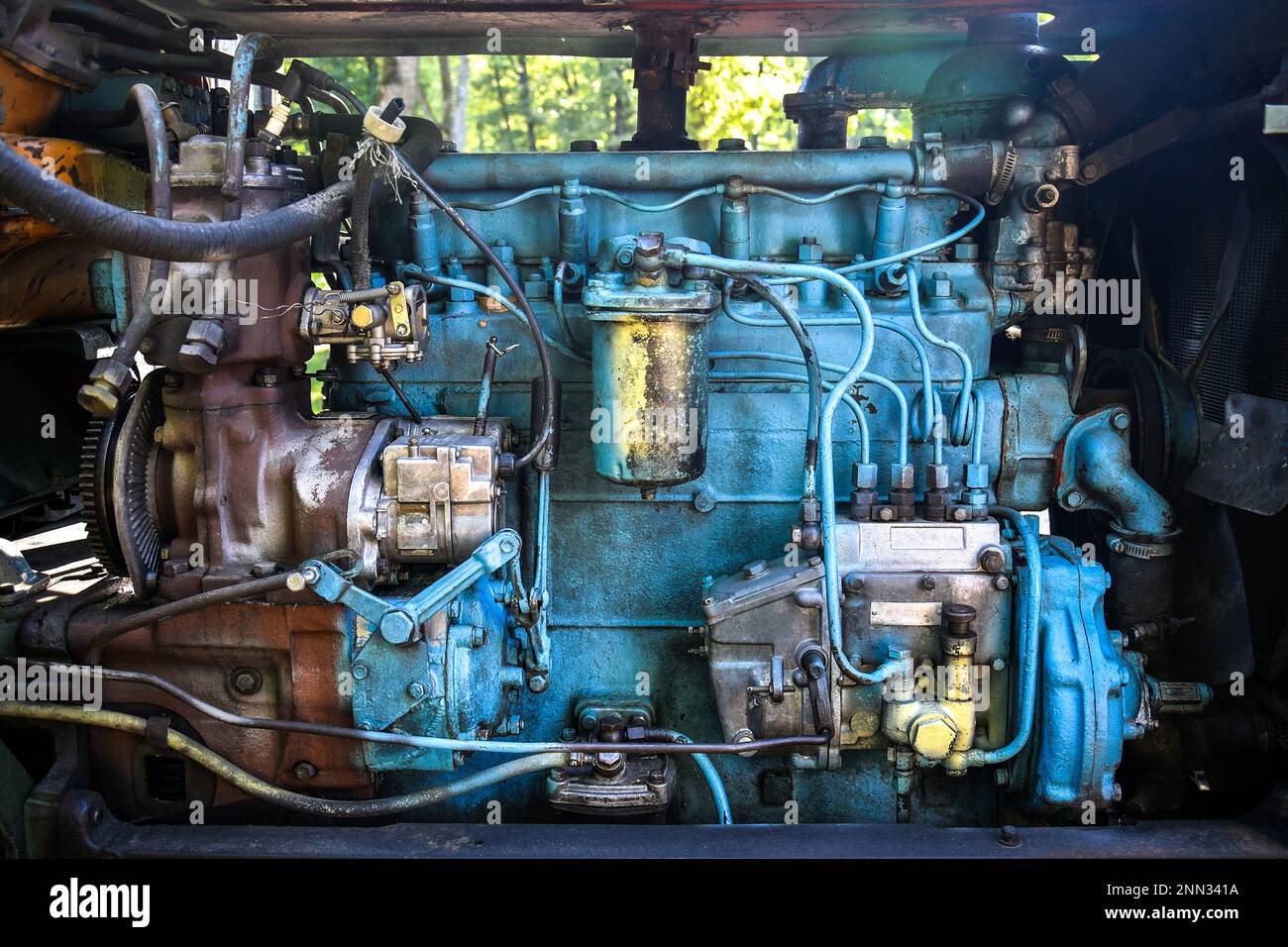 Diesel engine of an old tractor. Lots of metal tubes. Painted in blue ...