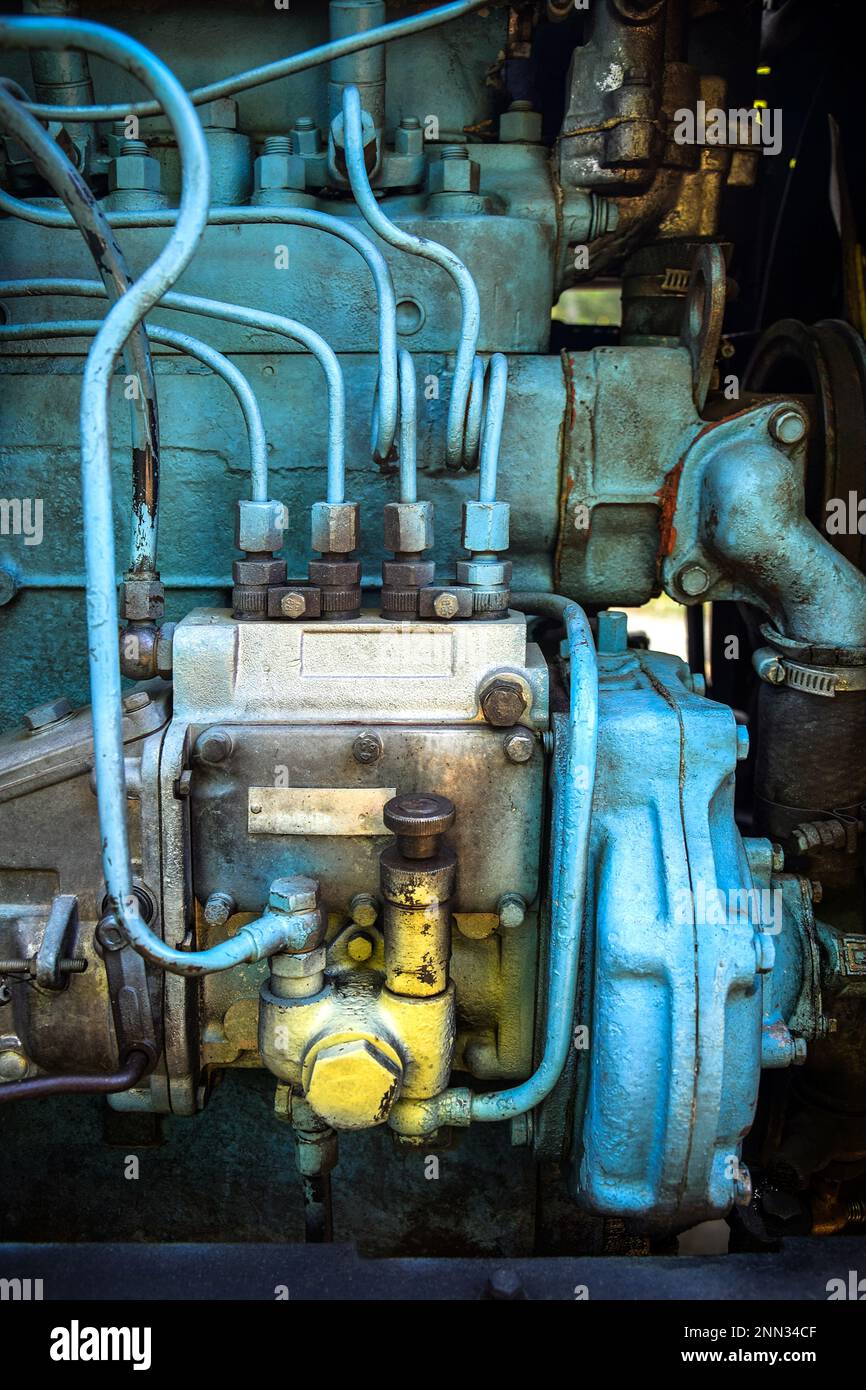 Diesel engine of an old tractor. Lots of metal tubes. Painted in blue ...