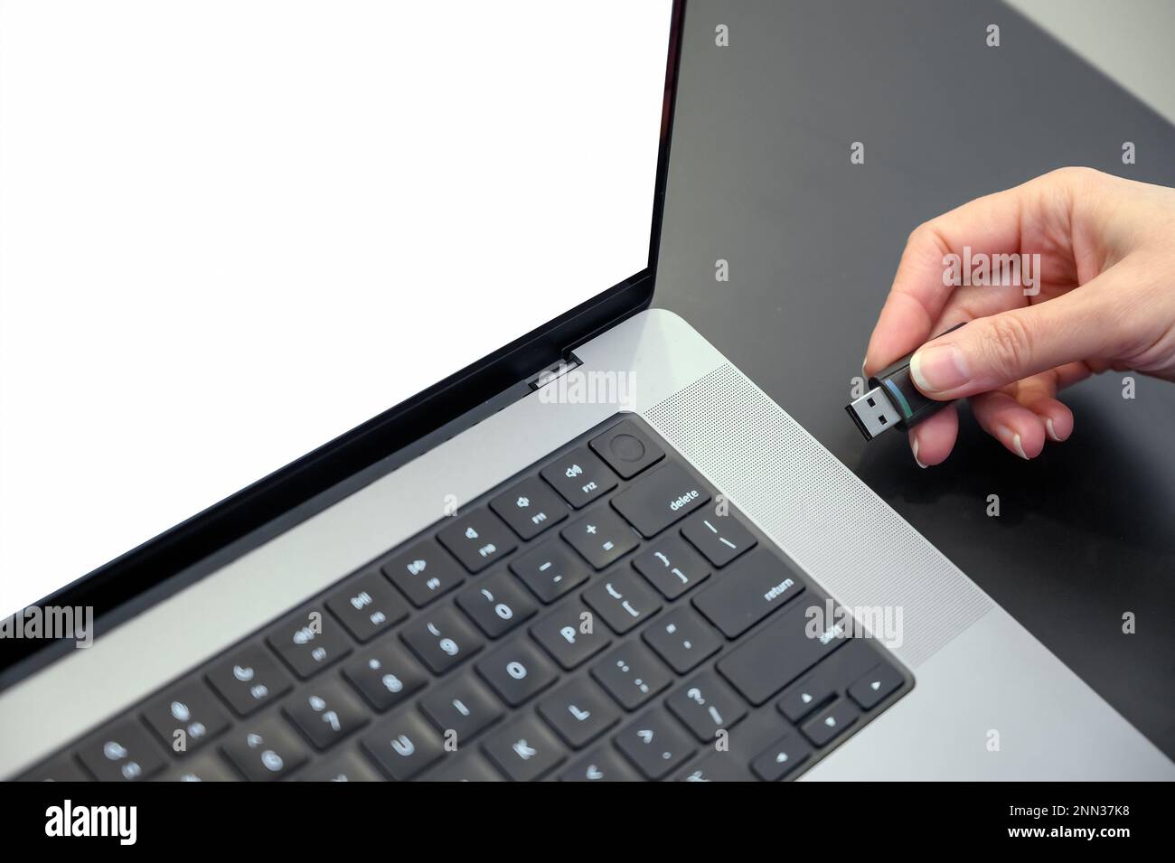 A hand is holding a usb flash drive over a laptop keyboard with a blank ...