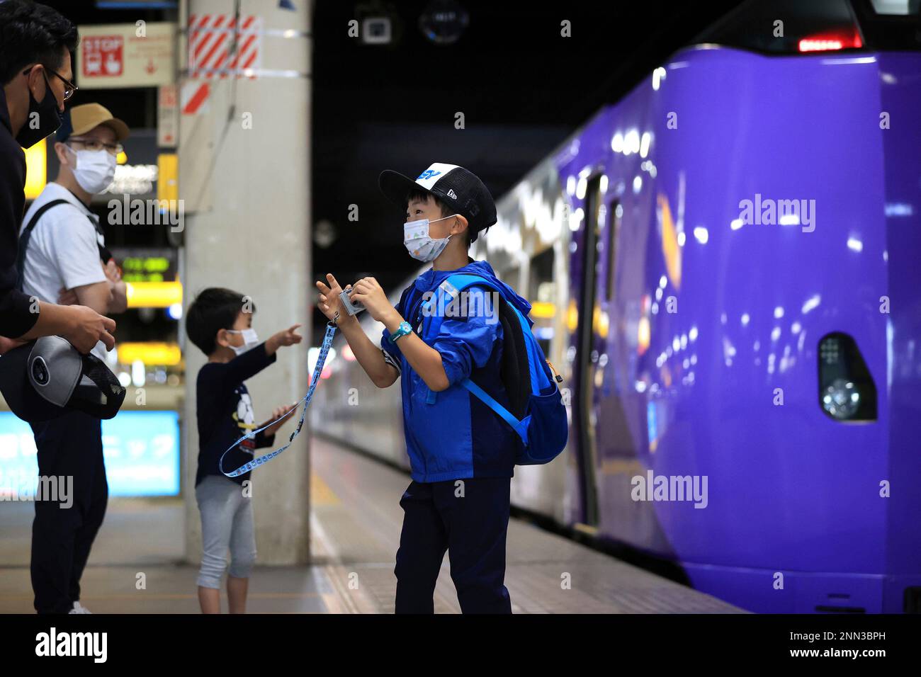 Railway buff boy poses in front of the Furano Lavender Express at JR Sapporo Station in Hokkaido ...