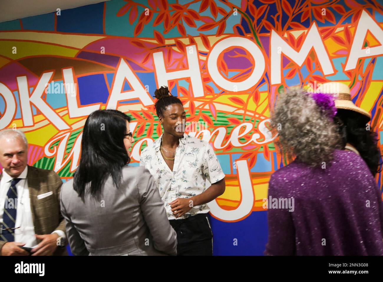 Muralist Alexander Tamahn poses for photos with guest as his new public ...