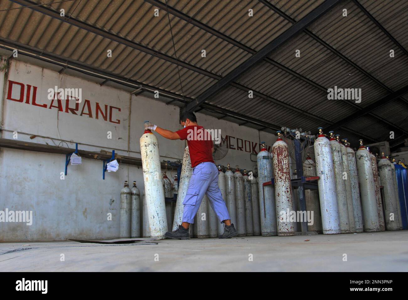 Workers refill oxygen tanks at an oxygen station to be distributed to ...