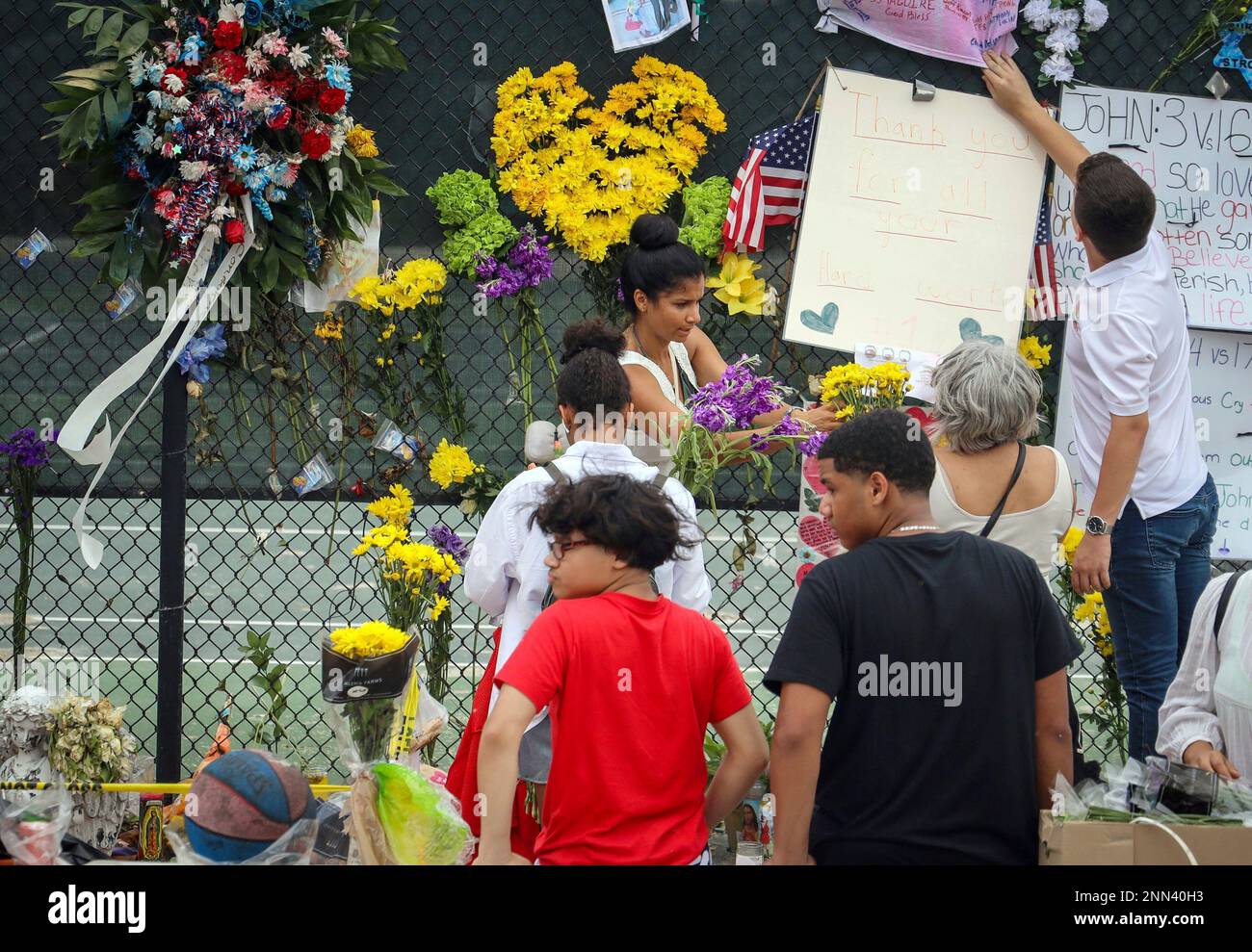 Volunteers along with locals replace dead flowers with fresh ones at a ...