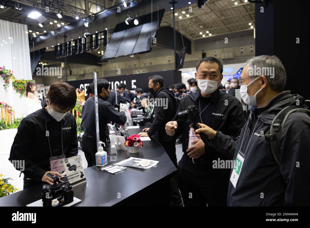 FUJIFILM exhibitor explains their company’s products to a visitor at ... FUJIFILM exhibitor explains their company’s products to a visitor at ...