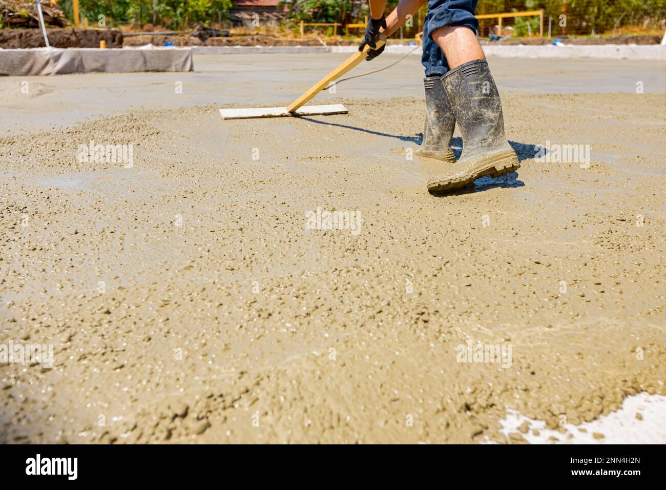 Rigger in rubber boots, worker is using wooden handmade handcraft tool ...