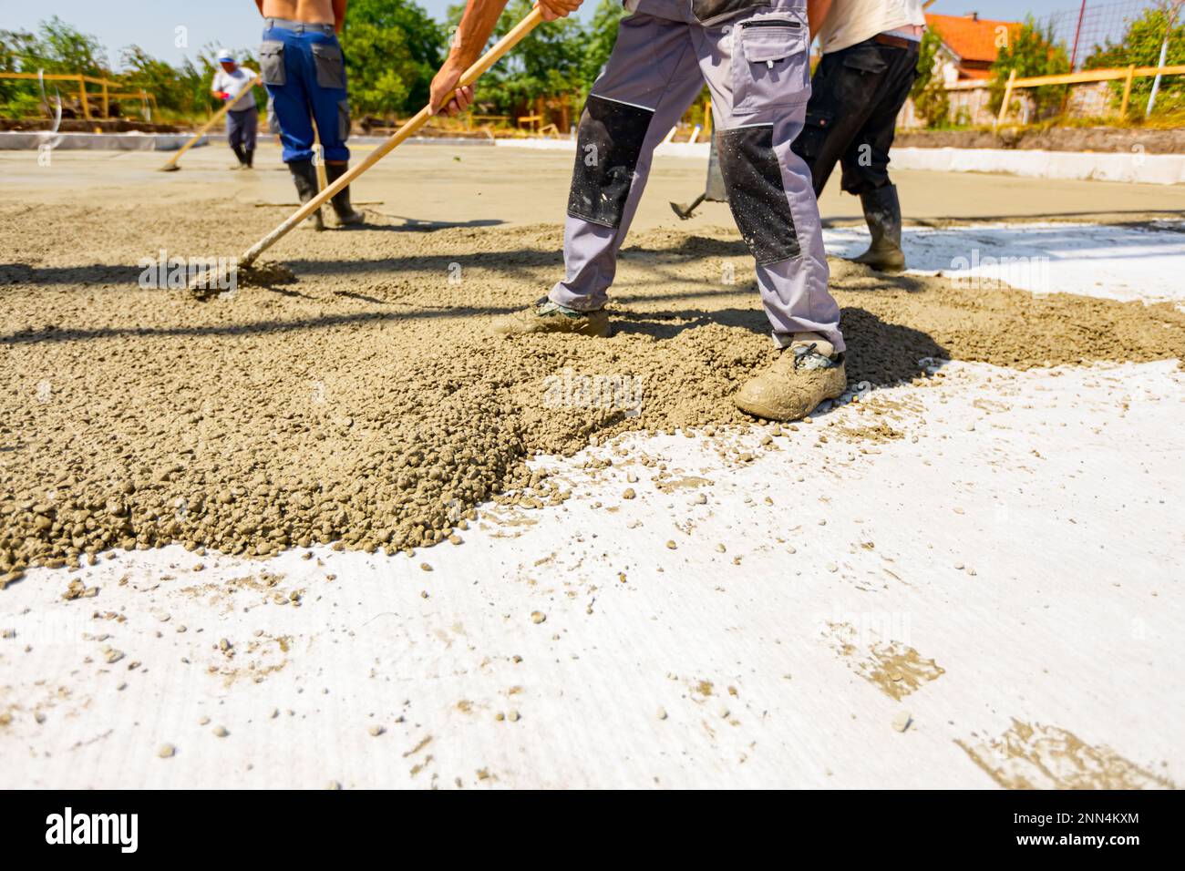 Construction worker, rigger is using rake to spreading, leveling ...