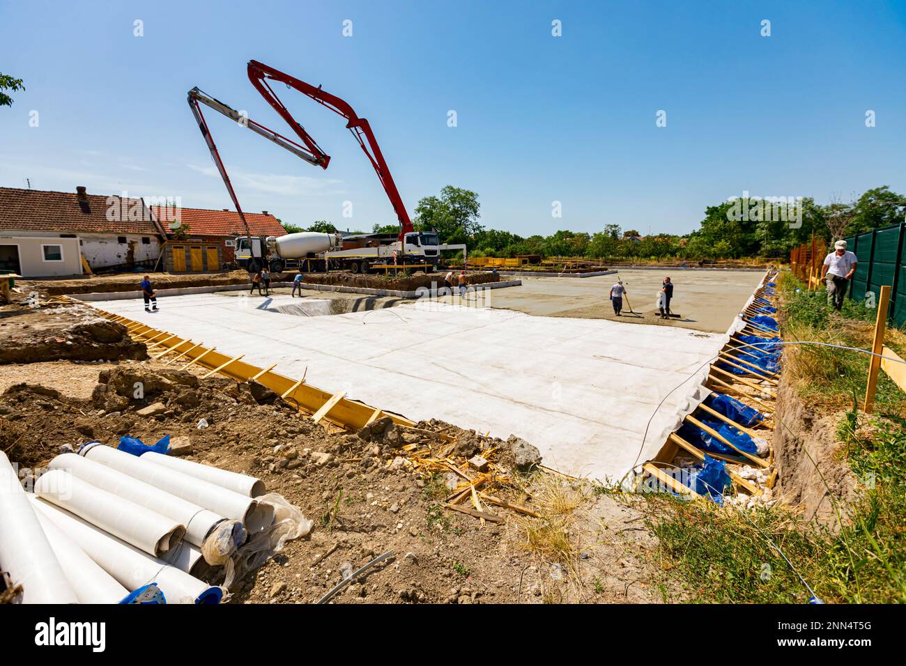 Construction site, mixer truck pouring fresh concrete into pump machine ...
