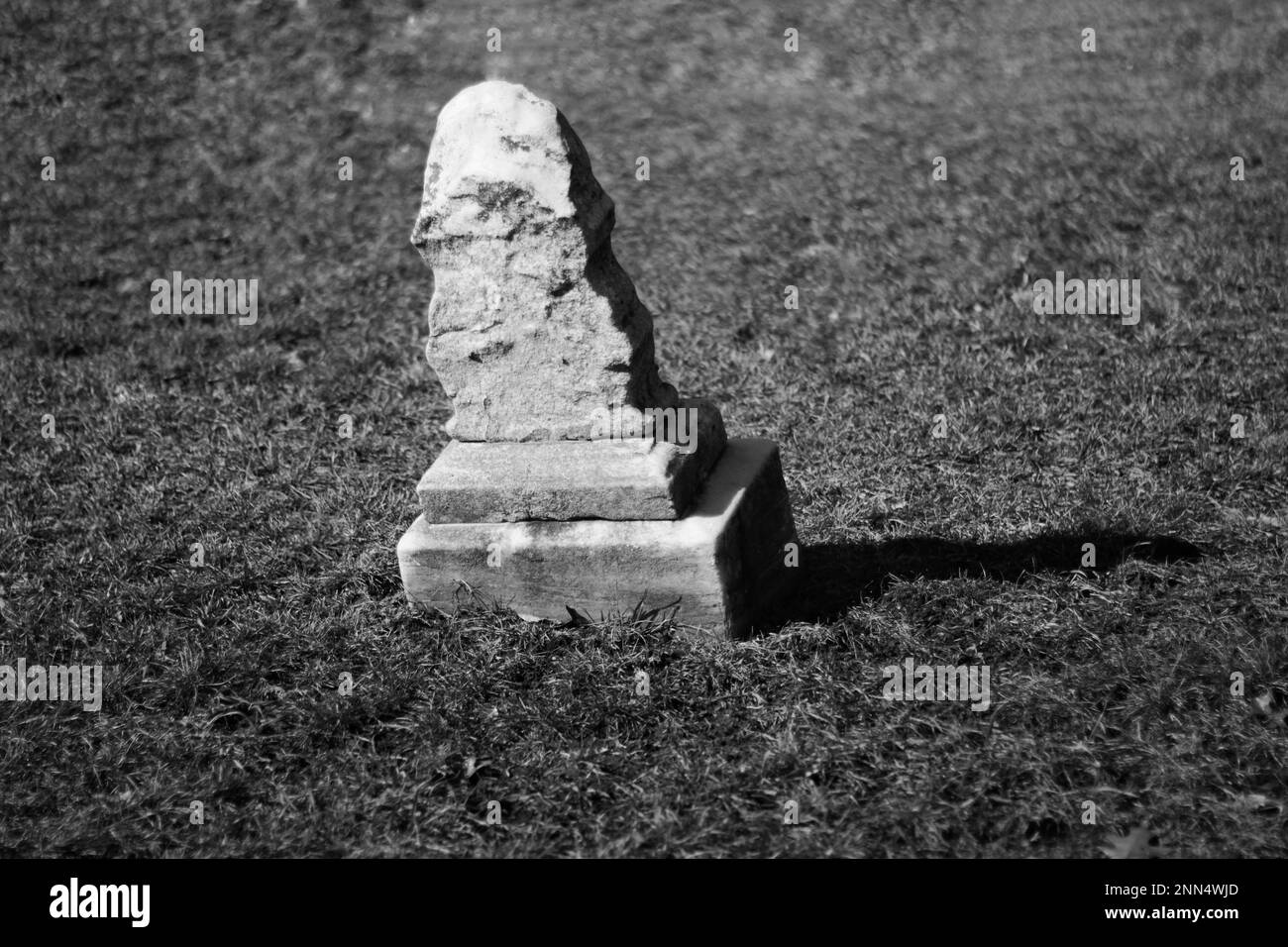 An old worn limestone tombstone about to fall over in the cemetery in a ...