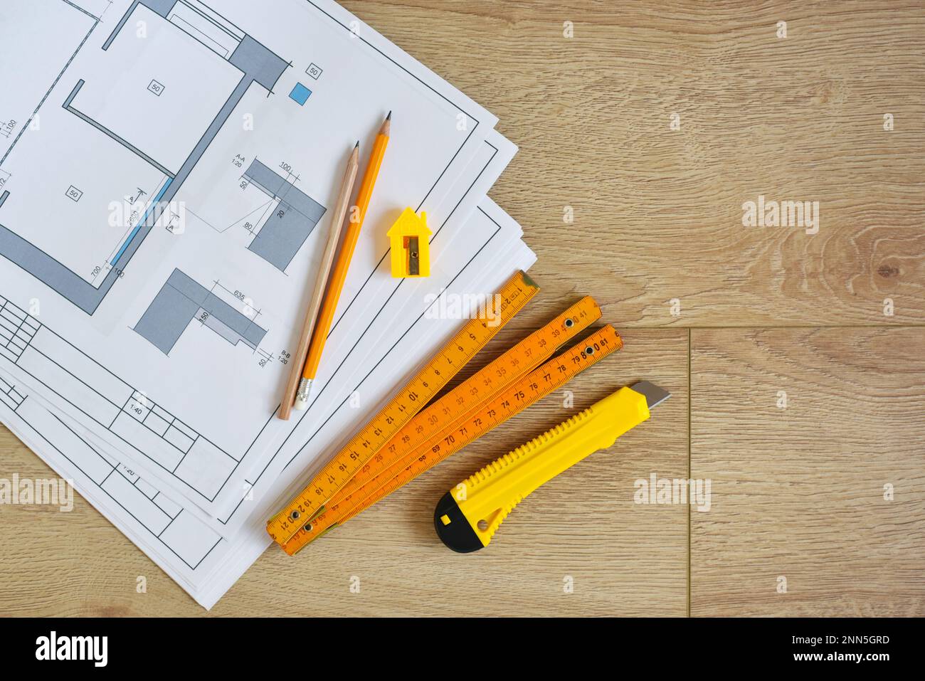 Architectural drawings and pencils, ruler, clerical knife on wooden ...