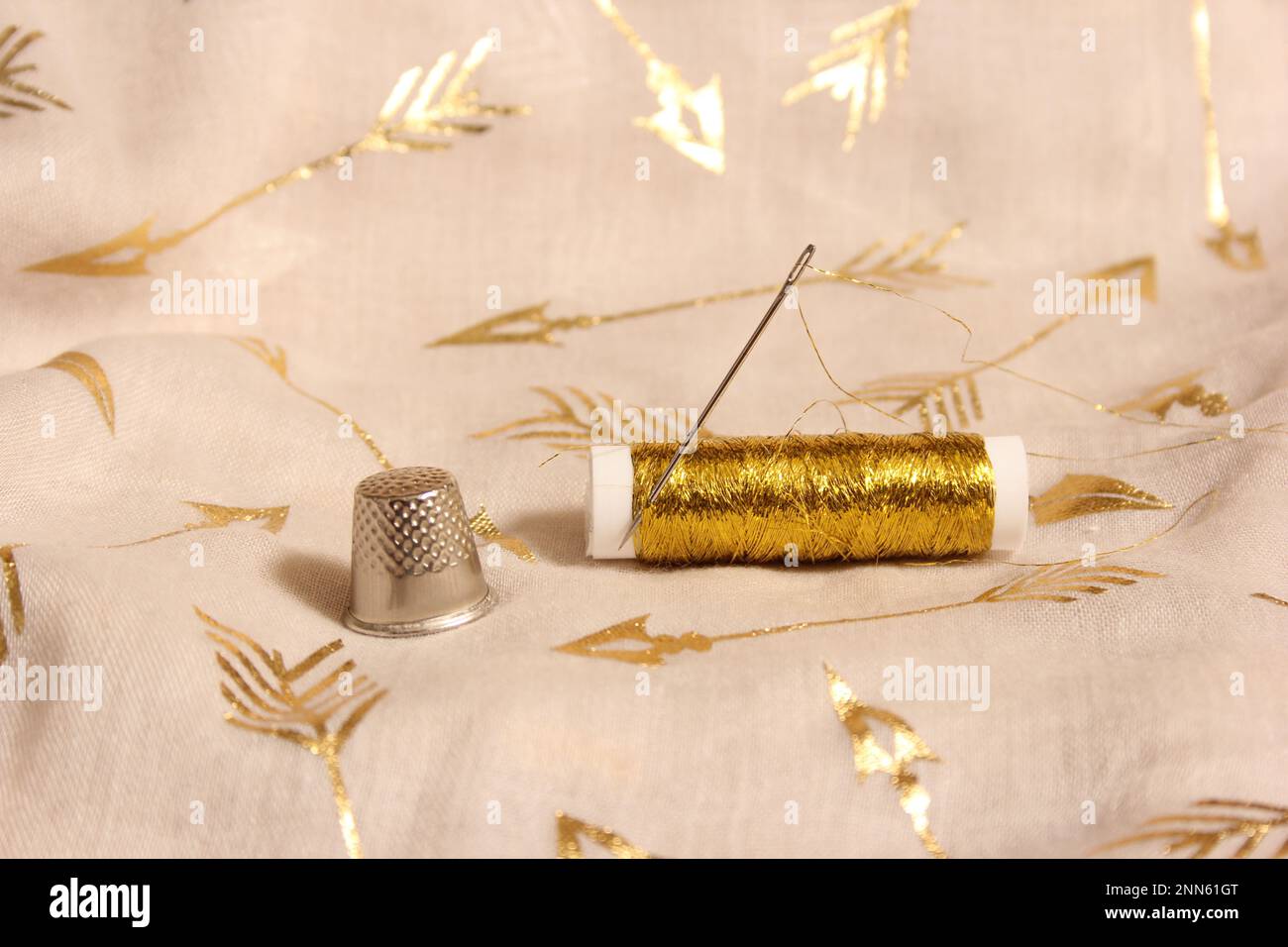 Spool of Gold Thread With Thimble on Metallic Chiffon Fabric Stock ...