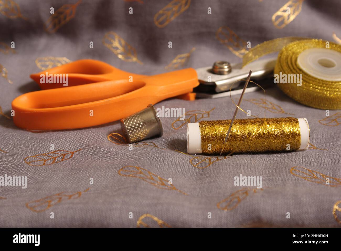 Spool of Metallic Gold Thread on Gray and Gold Fabric Stock Photo - Alamy