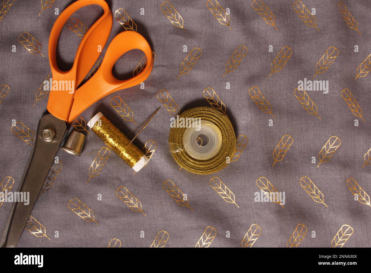 Spool of Metallic Gold Thread on Gray and Gold Fabric Stock Photo - Alamy