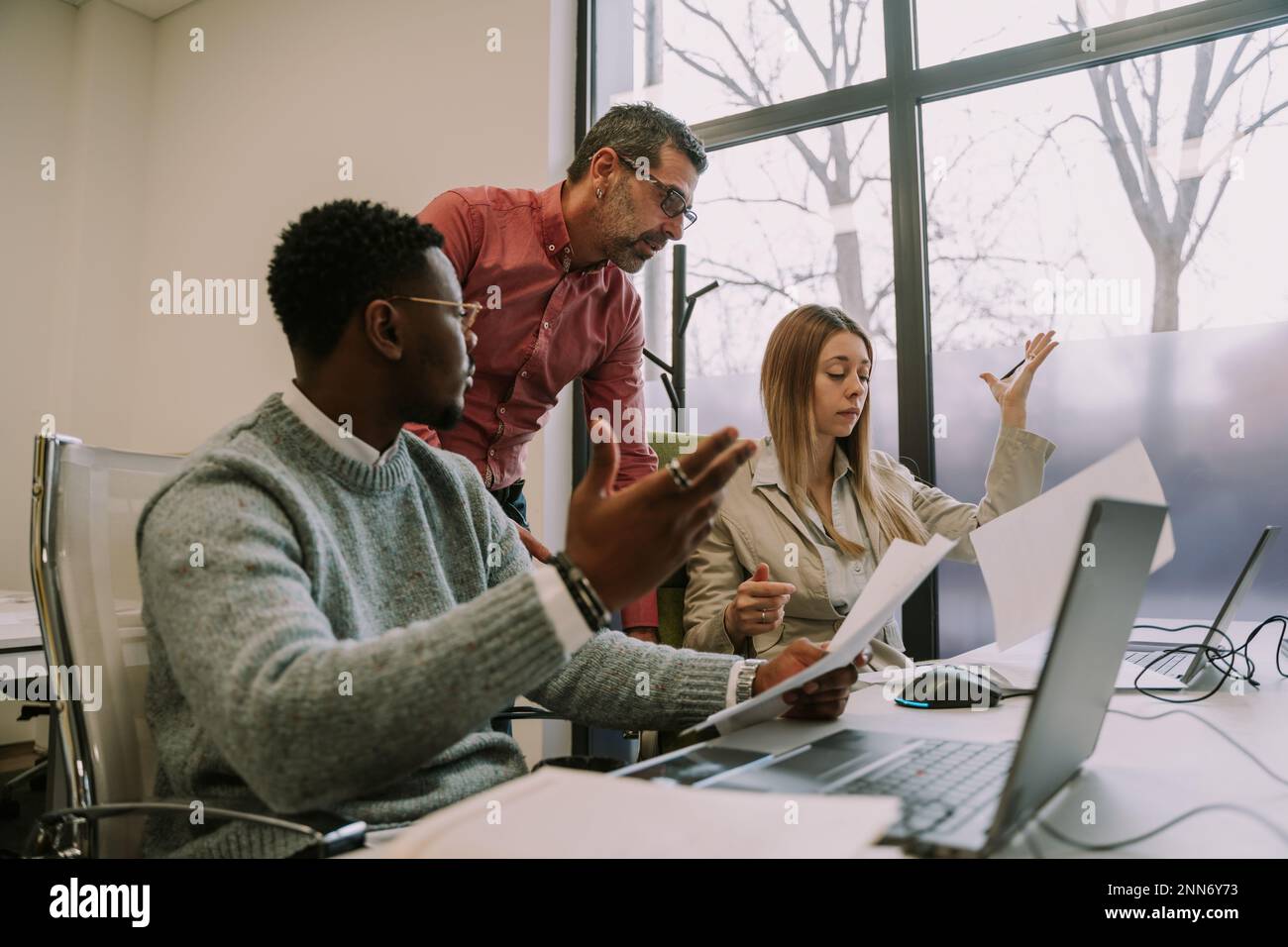 Two office employees reading the documents and typing on their laptops ...