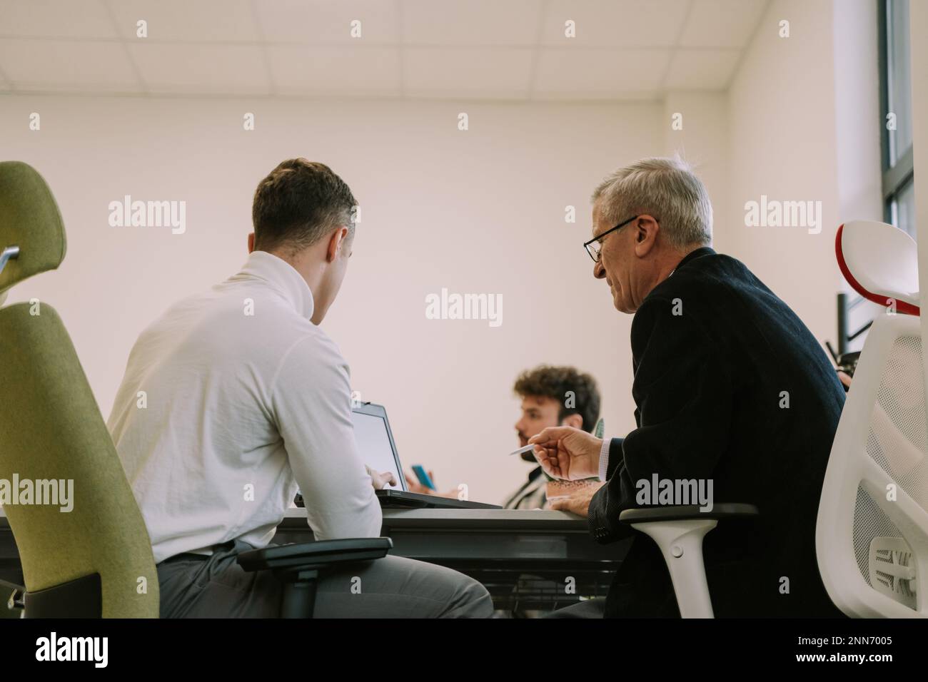 Senior male guiding and tutoring the new young employee at the office ...