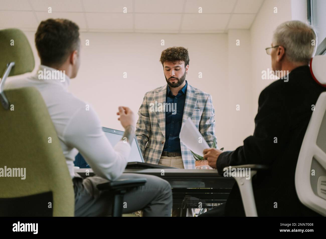 Disappointed and angry boss overlooking and correcting his employees at ...