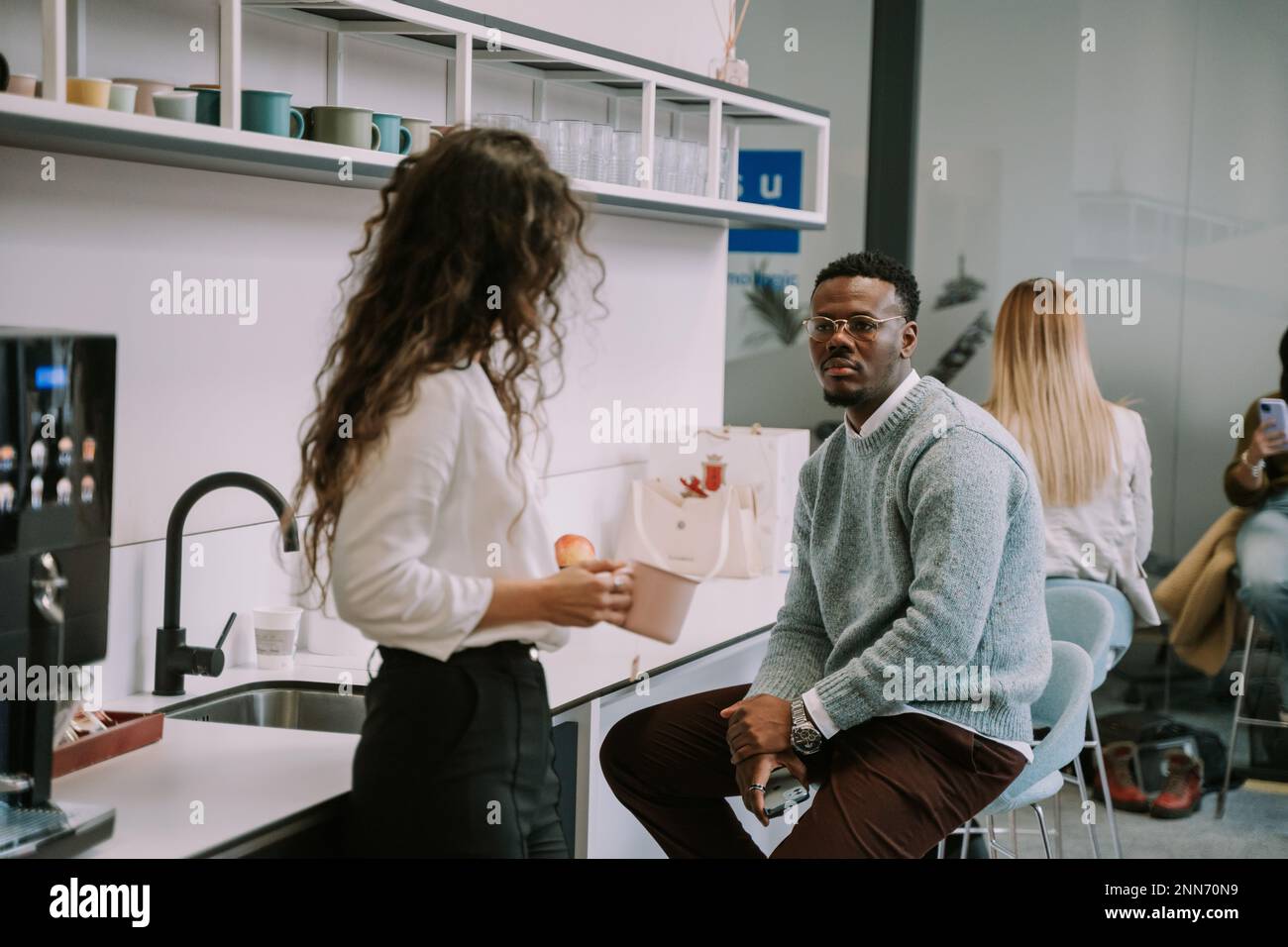 A handsome businessman listening to his female colleague explaining ...
