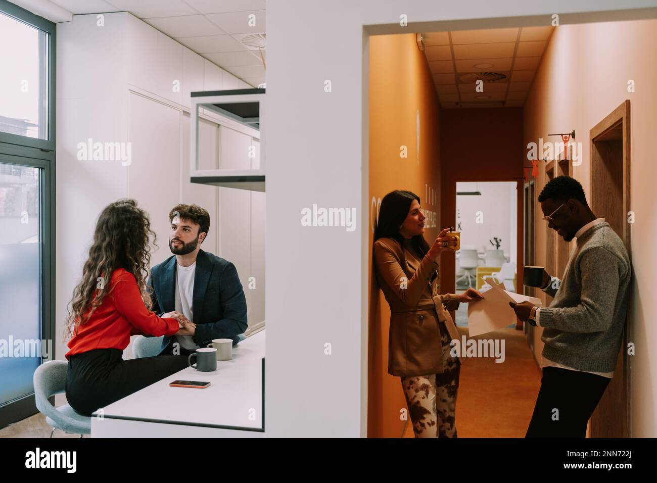 Two multiracial male colleagues flirting with their caucasian female ...