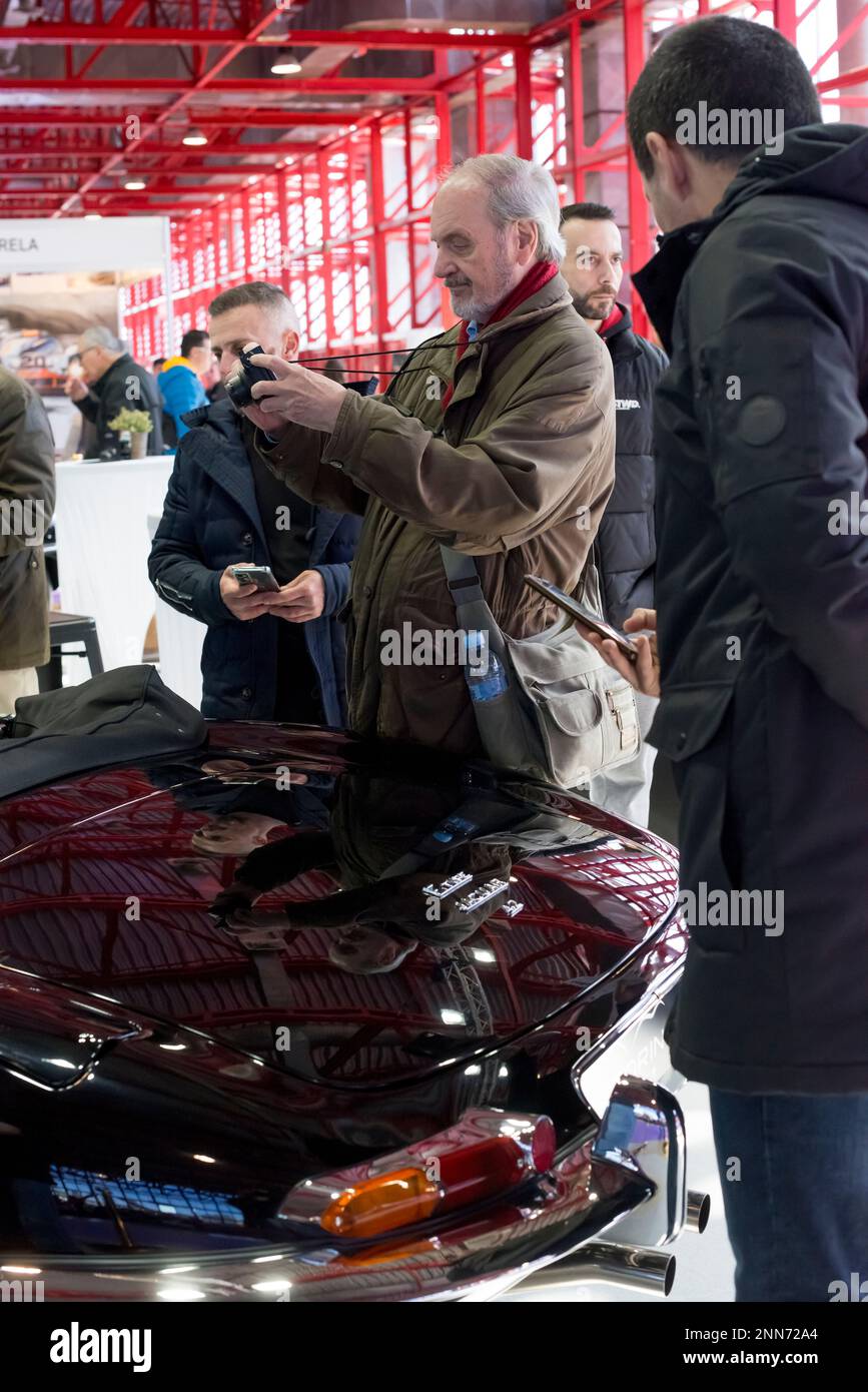 A man taking a photo of a Jaguar E Type at the ClassicMadrid exhibition ...