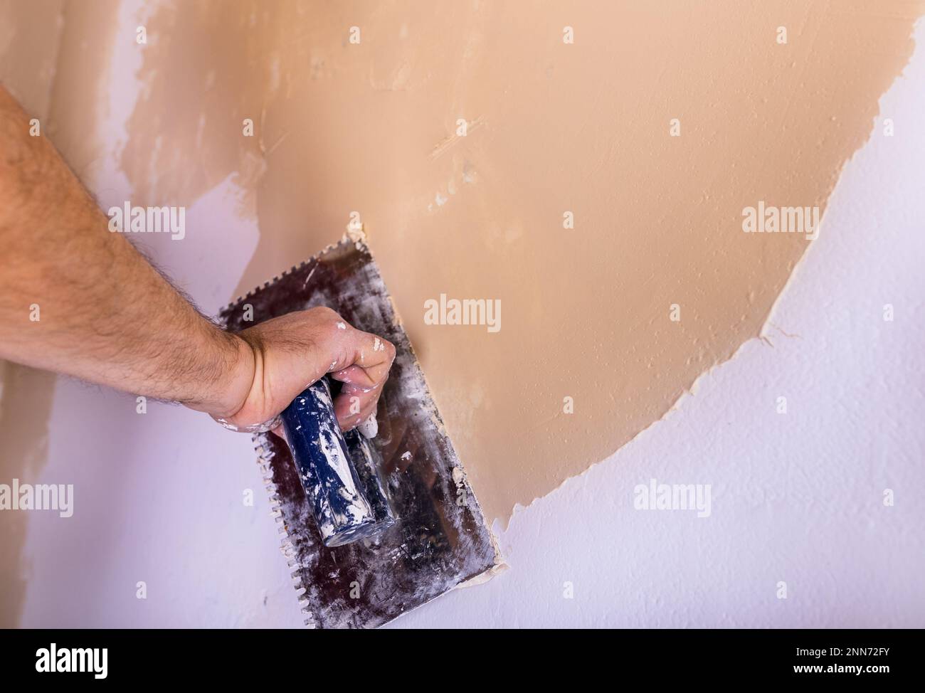 Close up of male hand putting plaster on wall in home renovation ...
