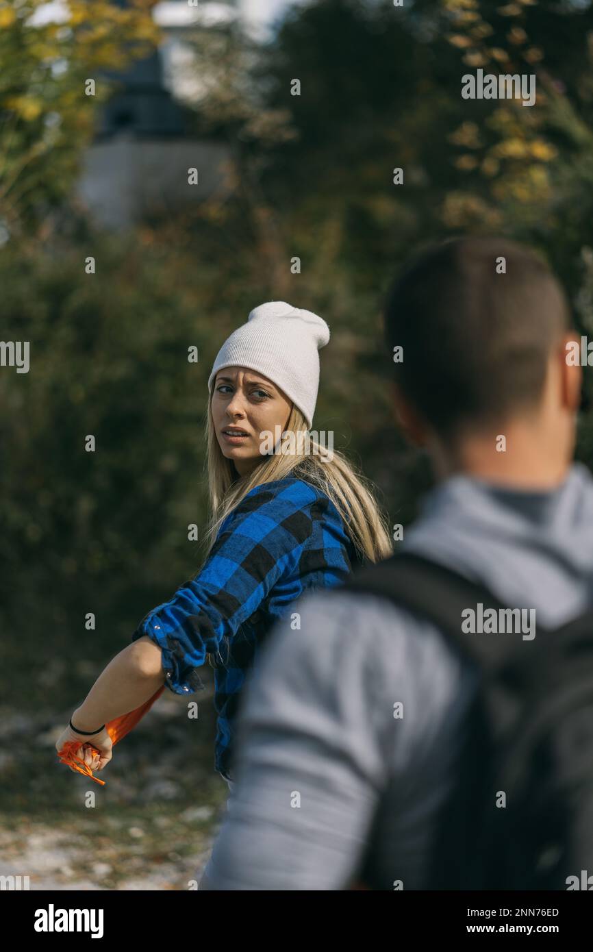 A male hiker talking to his friends. One girl is looking back confused ...