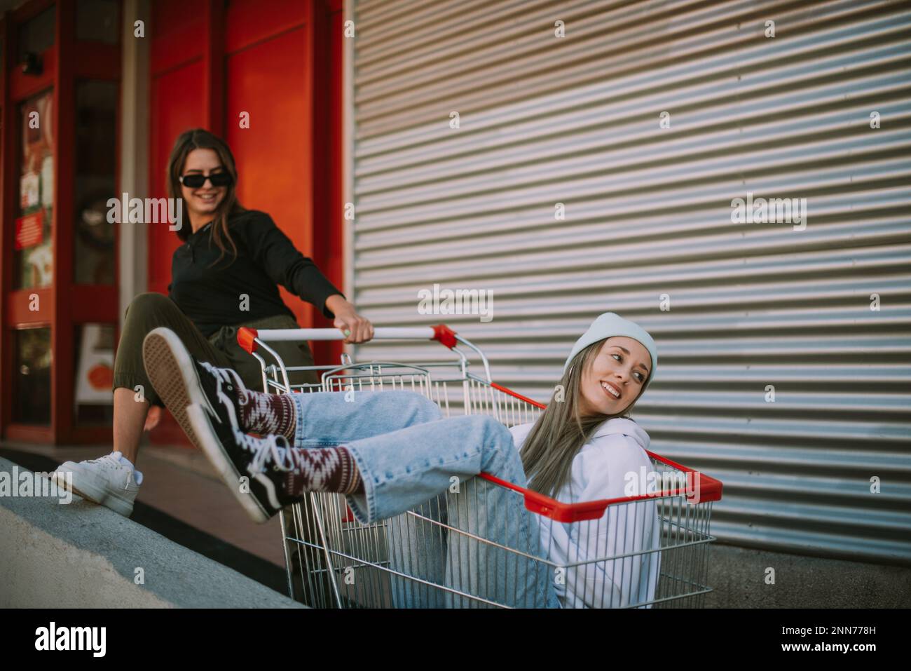 Two pretty best friends smiling while one of them is sitting in a ...