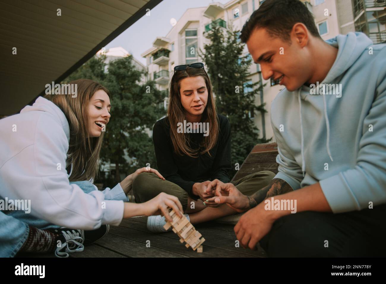 Blonde girl moving the jenga while sitting with her friends on the ...