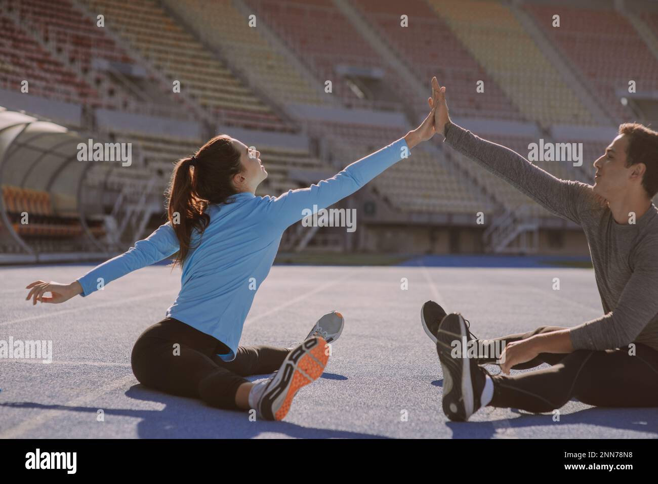 Two pretty friends are giving each other high five while stretching ...