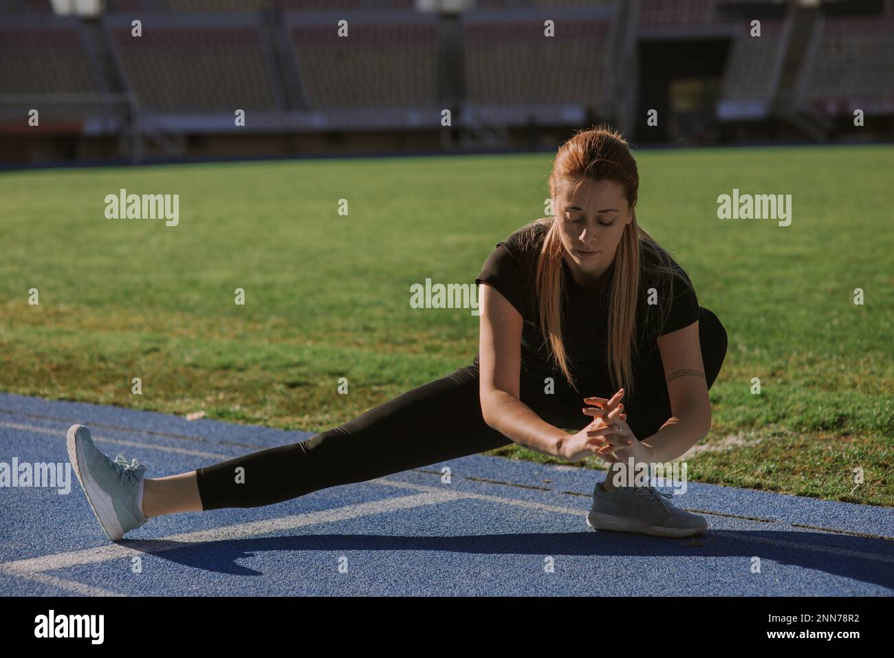 Lovely girl is exercising at the stadium, early in the morning. She is ...