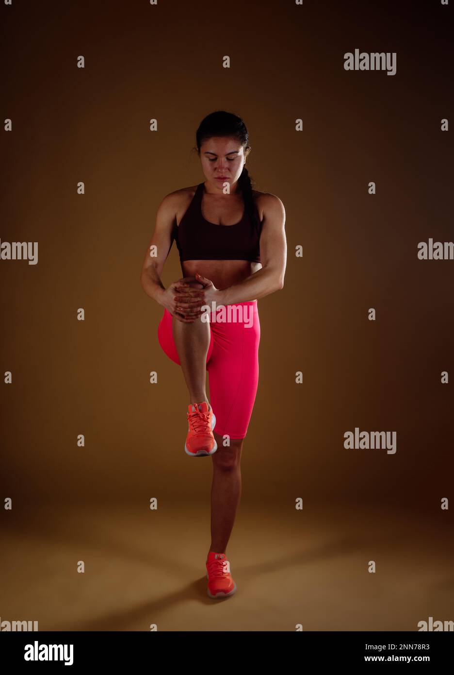 A front view photo of a strong woman in sportswear stretching her right ...