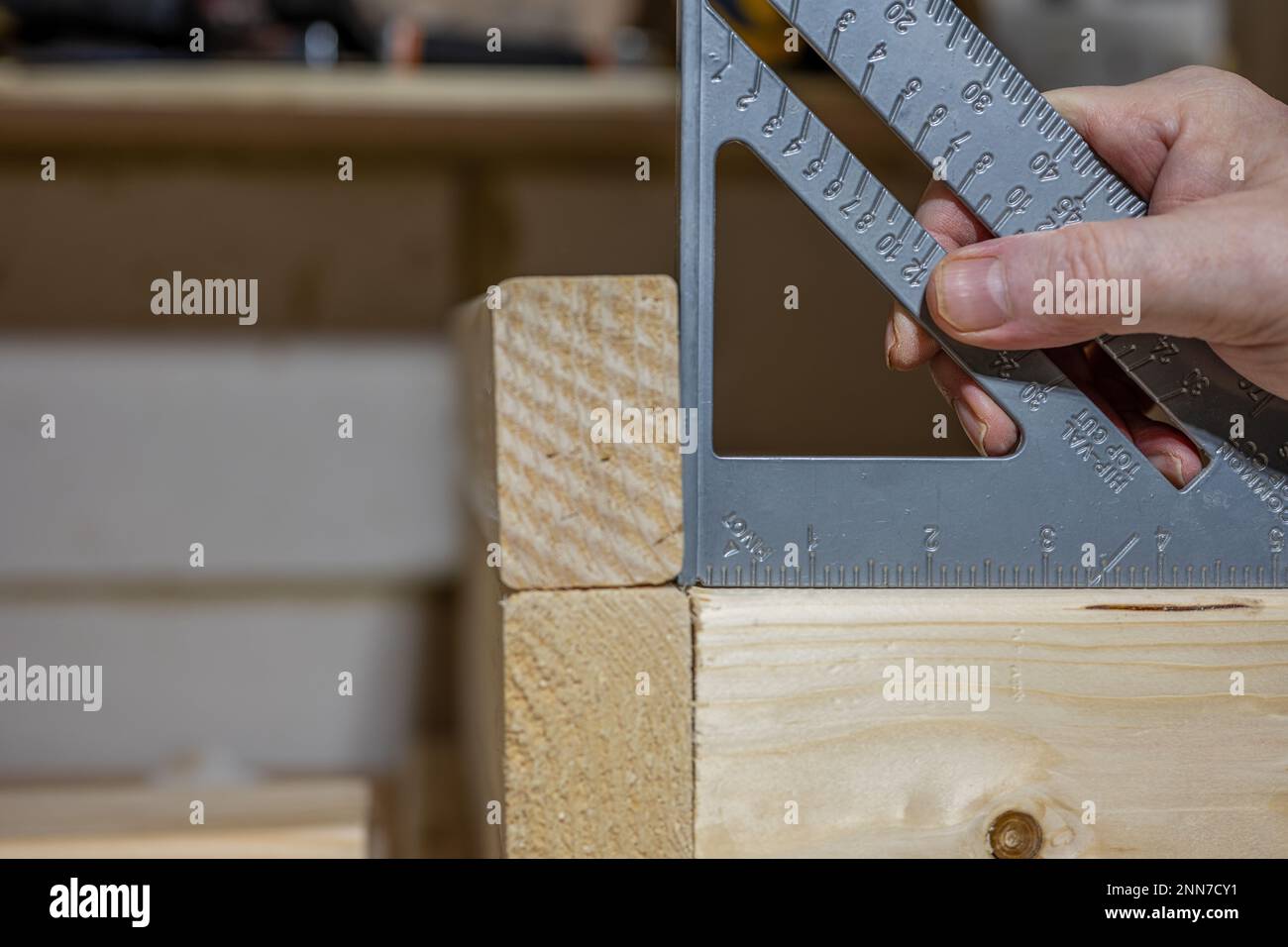 checking square with an aluminium tool against a timber lumber section ...