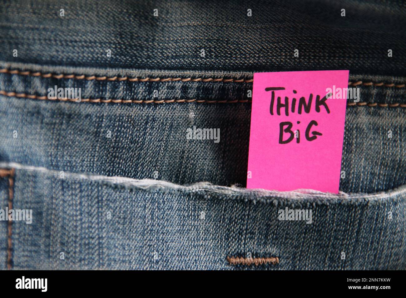 Motivational quotes inscription on a tag in a pocket of blue jeans ...