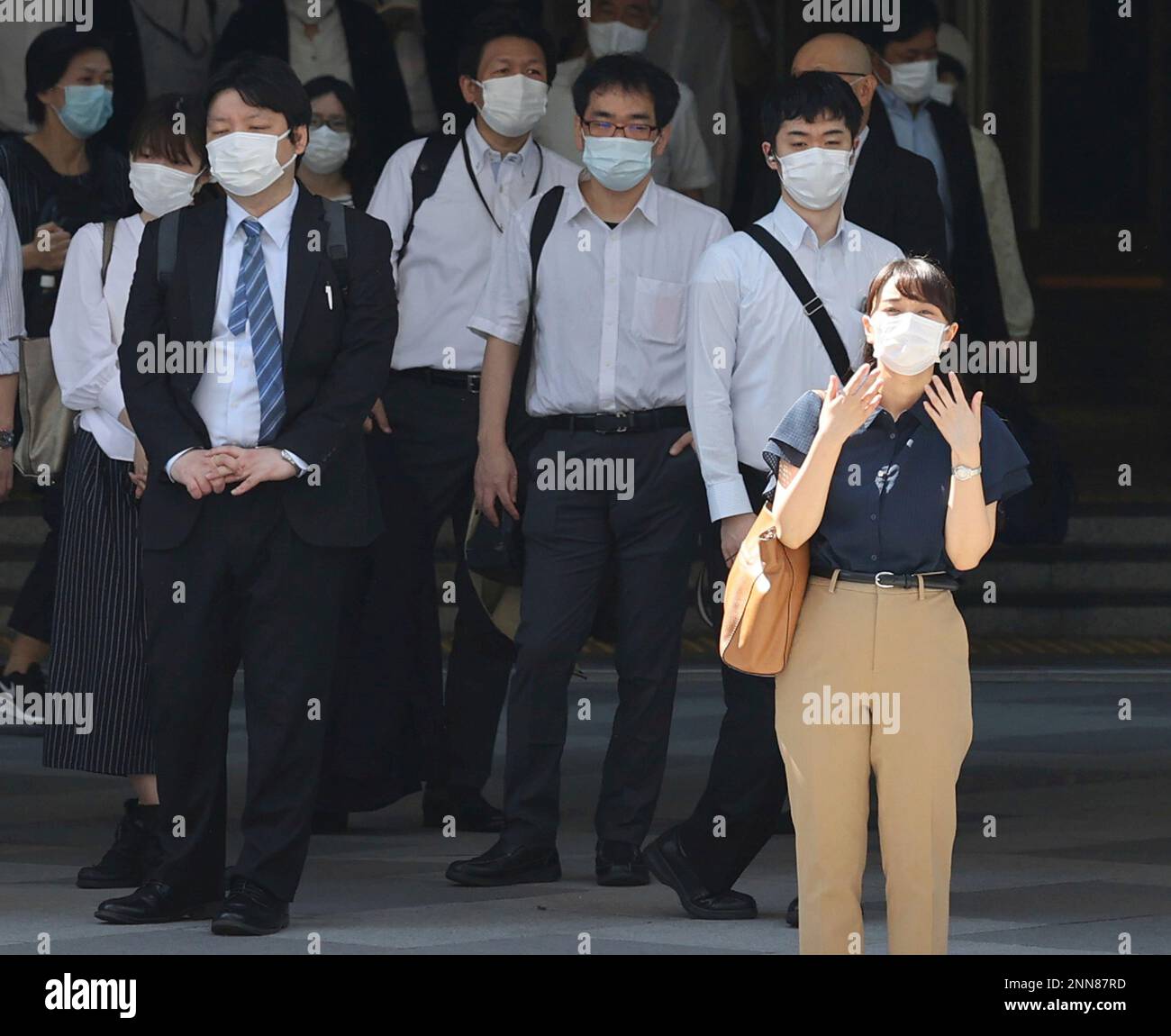 People wearing masks walk in strong sunlight near Tokyo Station in ...