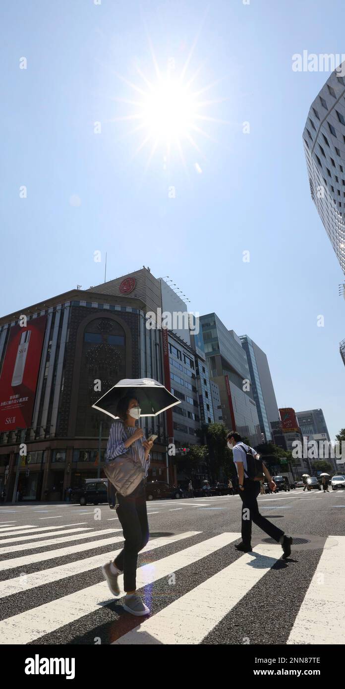 People wearing masks walk in strong sunlight in Ginza district, Tokyo ...