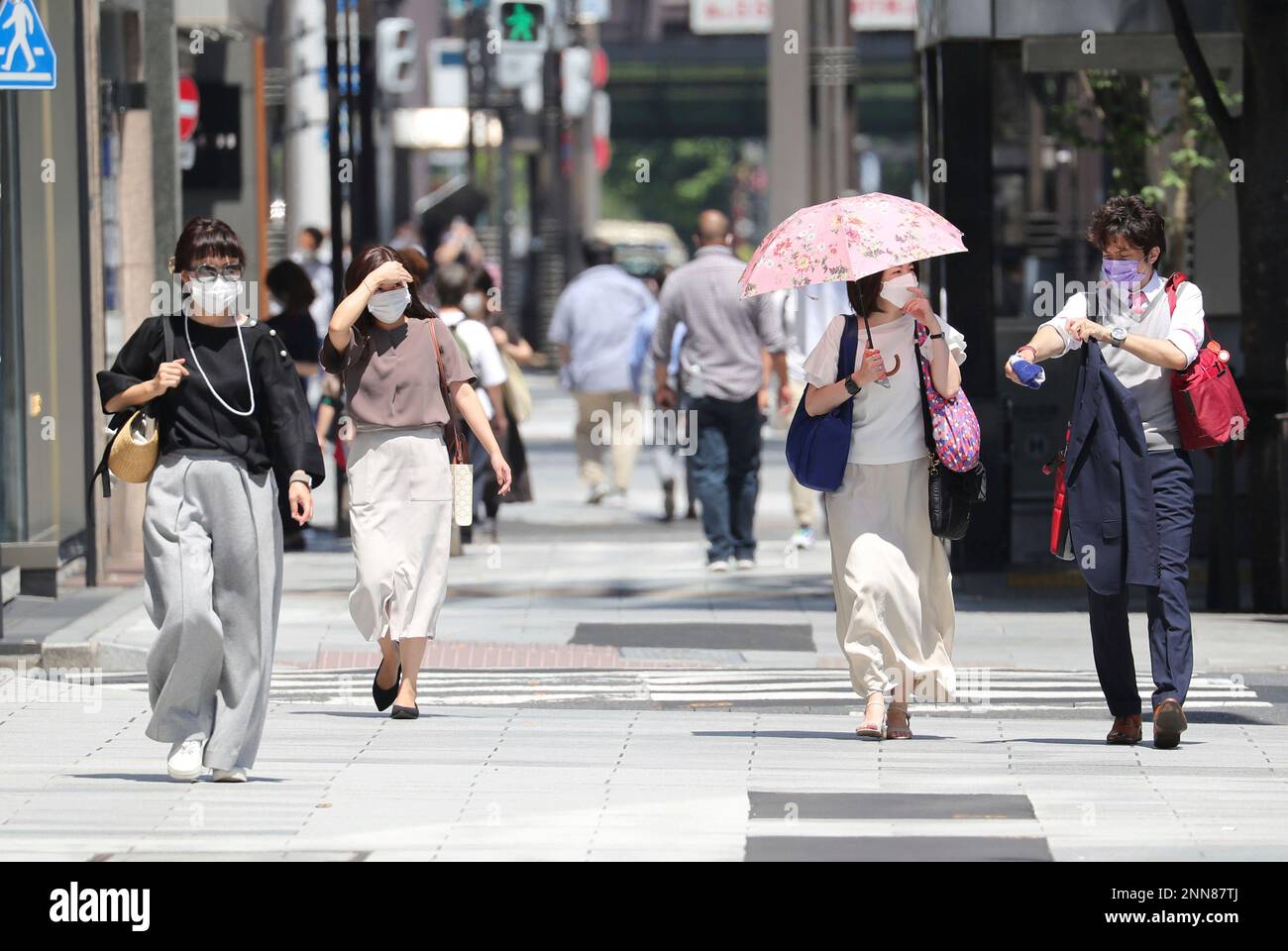 People wearing masks walk in strong sunlight in Ginza district, Tokyo ...