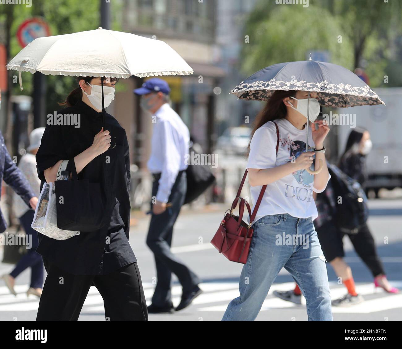 People wearing masks walk in strong sunlight in Ginza district, Tokyo ...