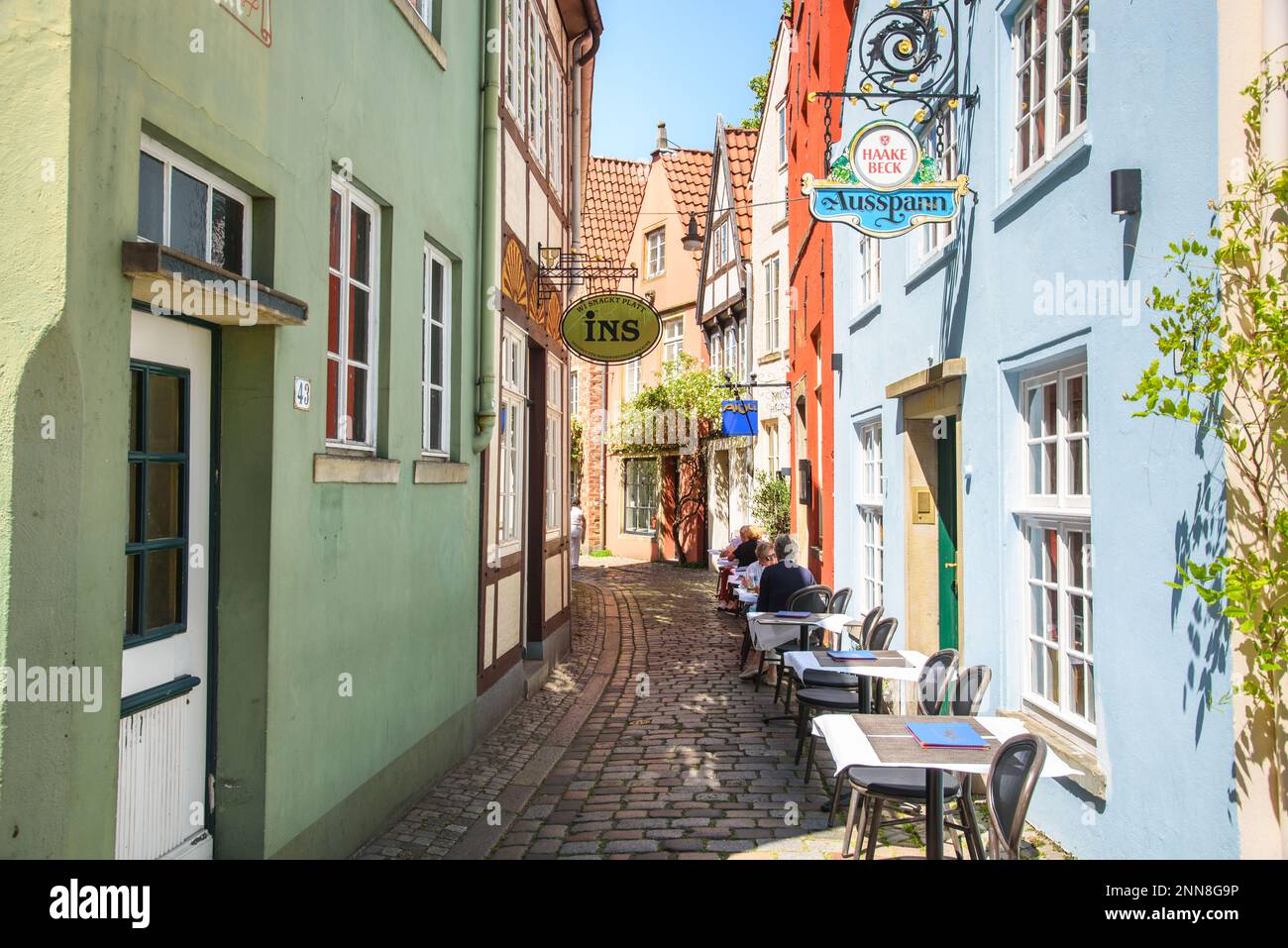 People having lunch outdoor in a reastaurant on a narrow cobbled street ...