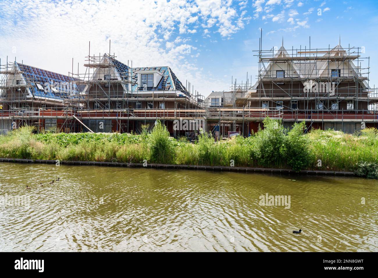 Houses under construction in a housing development along a canal on a ...