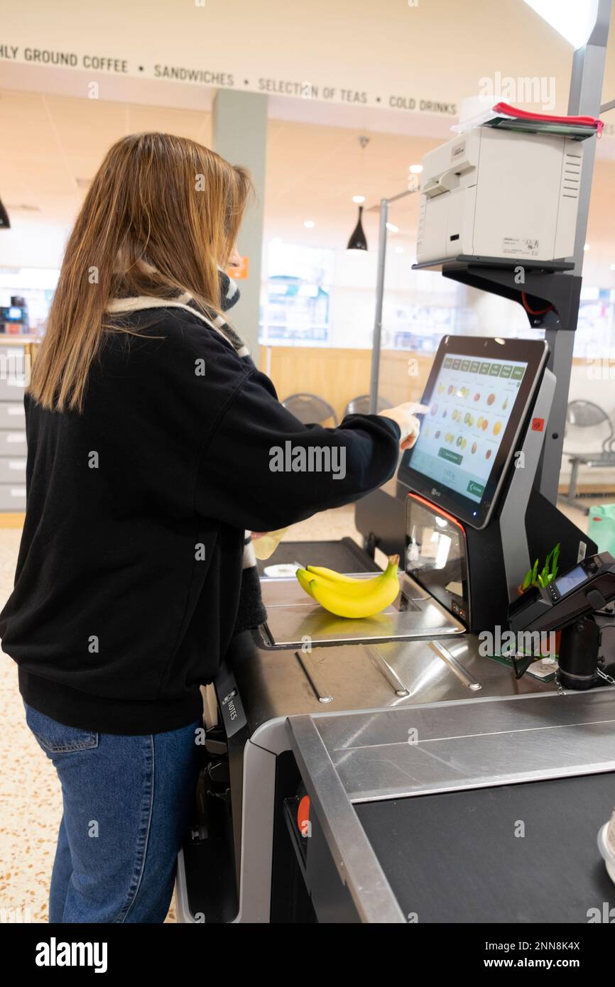 Young woman shopper rear back view paying for food shopping standing at ...