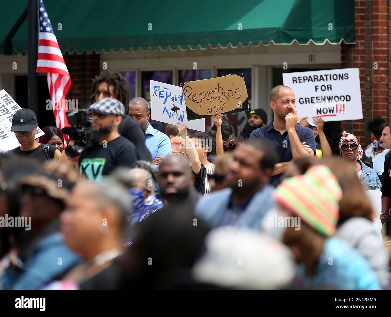 Protesters hold signs for reparations on the perimiter of a dedication ...