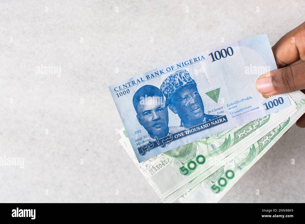 Hand holding the new Nigerian 1000 and 500 Naira notes on a white ...