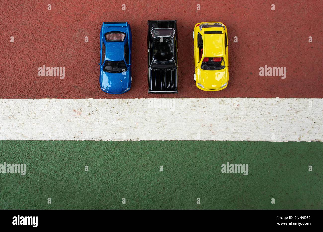 A photo of 3 toy cars placed at the edge of the court line, after ...