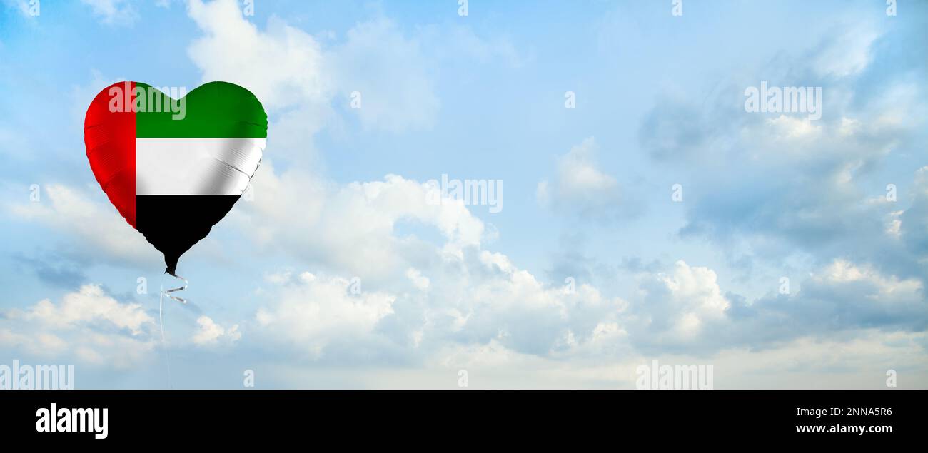 Flag of United Arab Emirates on heart-shaped balloon against sky clouds ...