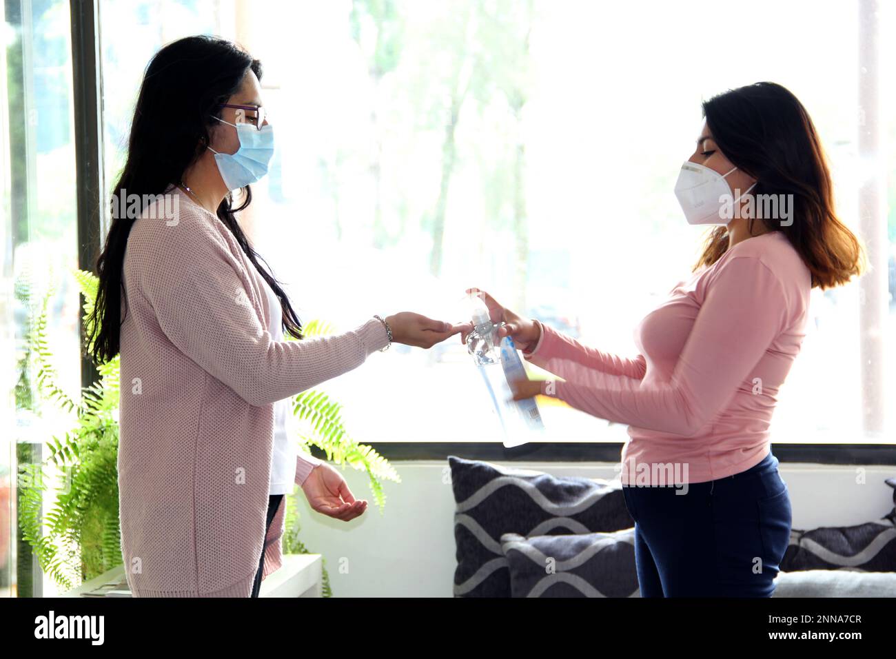 New normal, latin woman with protection mask receives woman with ...