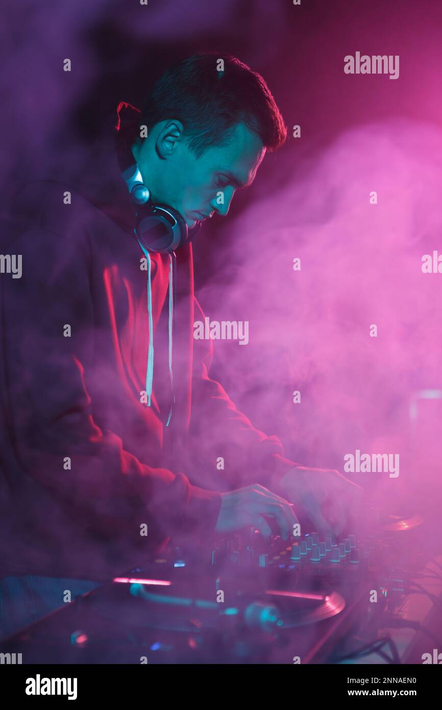 Club DJ mixing music in smoke and neon lights. Hip hop disc jockey ...