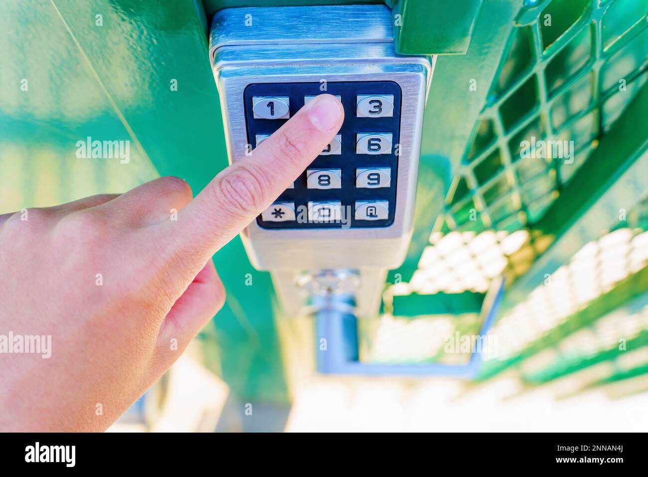 Hand enters a numeric code to open the gate lock Stock Photo - Alamy