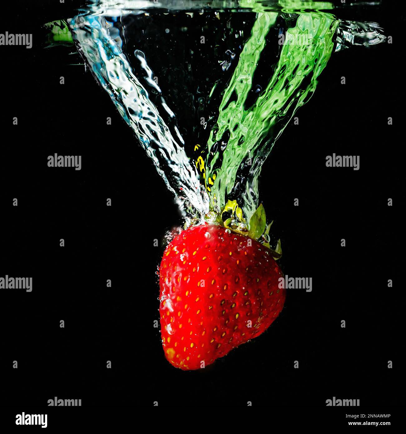 ripe strawberries fall into the water lifting splashes and air bubbles ...