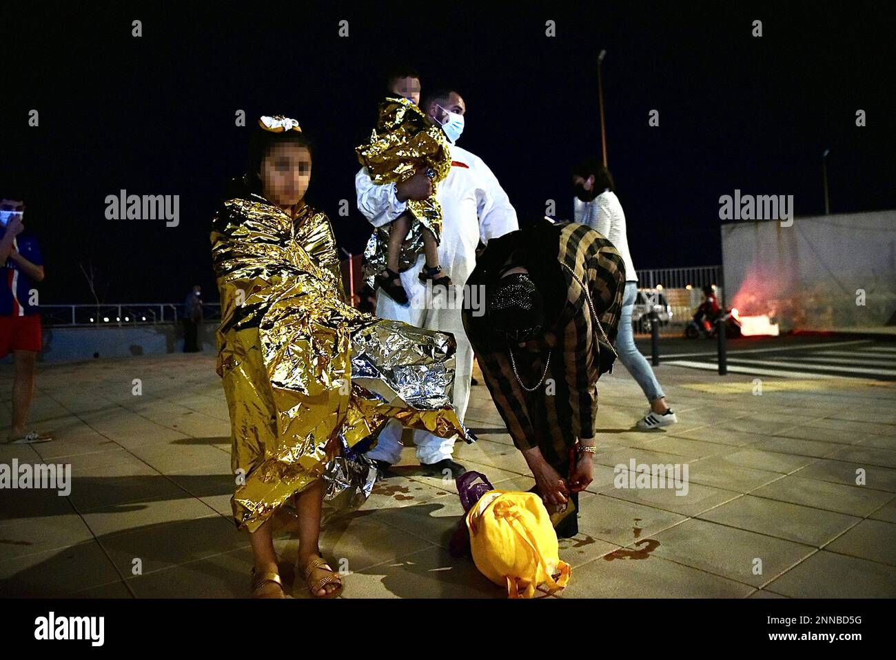 A migrant man holds a child accompanied by a woman and a little girl ...