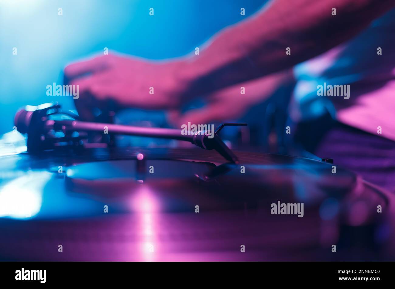 Club DJ paying music with vinyl records and turn table. Disc jockey ...