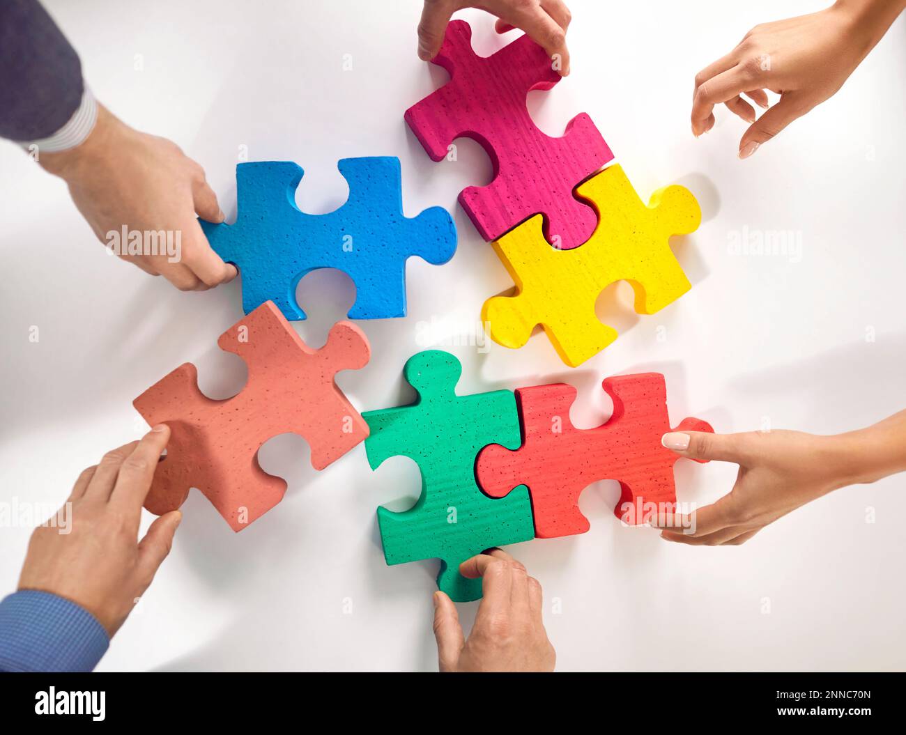 Business team matching colorful parts of a jigsaw puzzle to illustrate ...