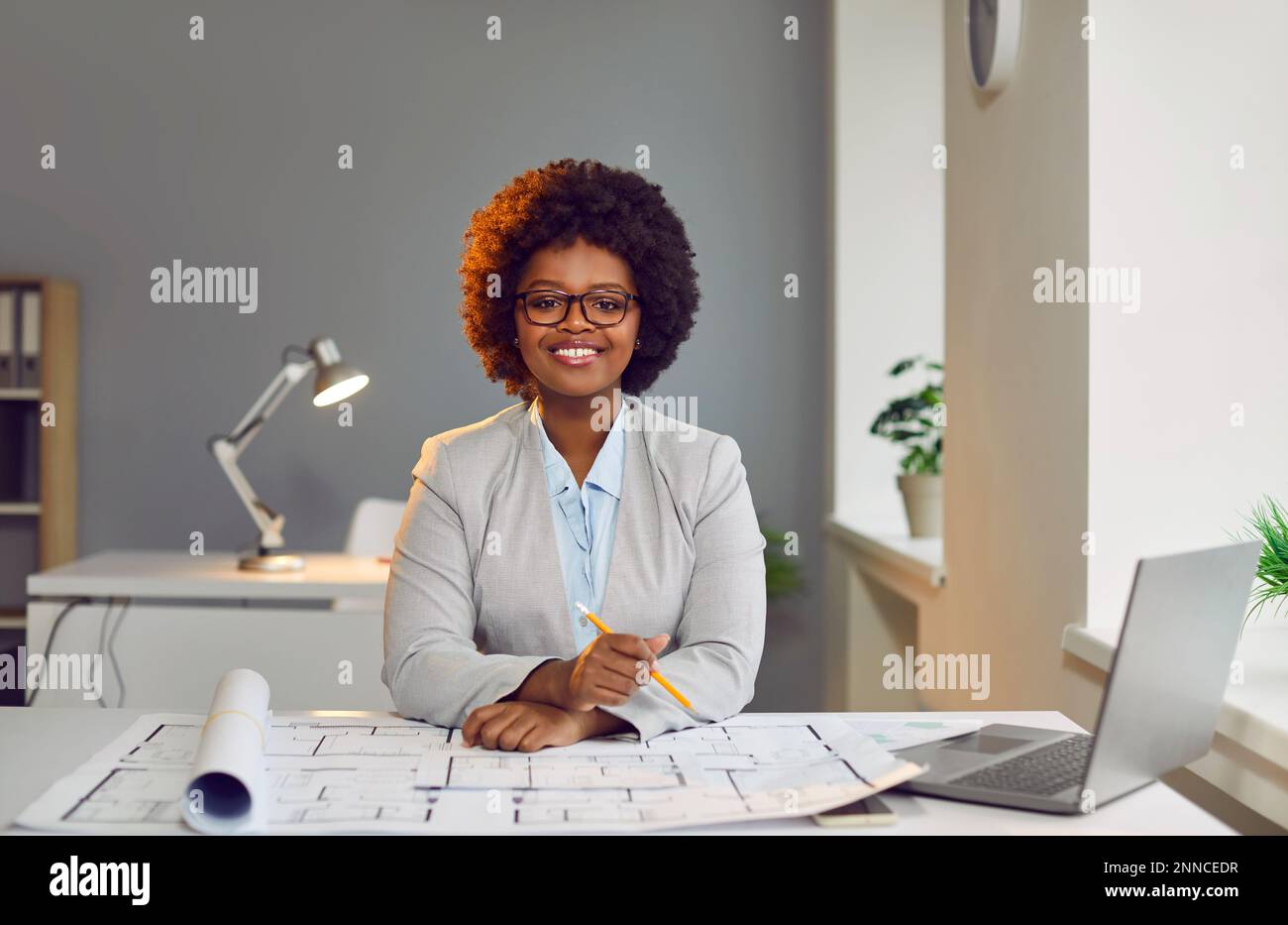 Happy, smiling African American woman architect sitting at her office ...